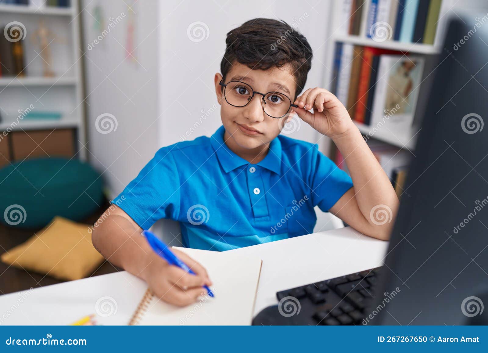 Adorable Hispanic Boy Student Using Computer Writing on Notebook at ...