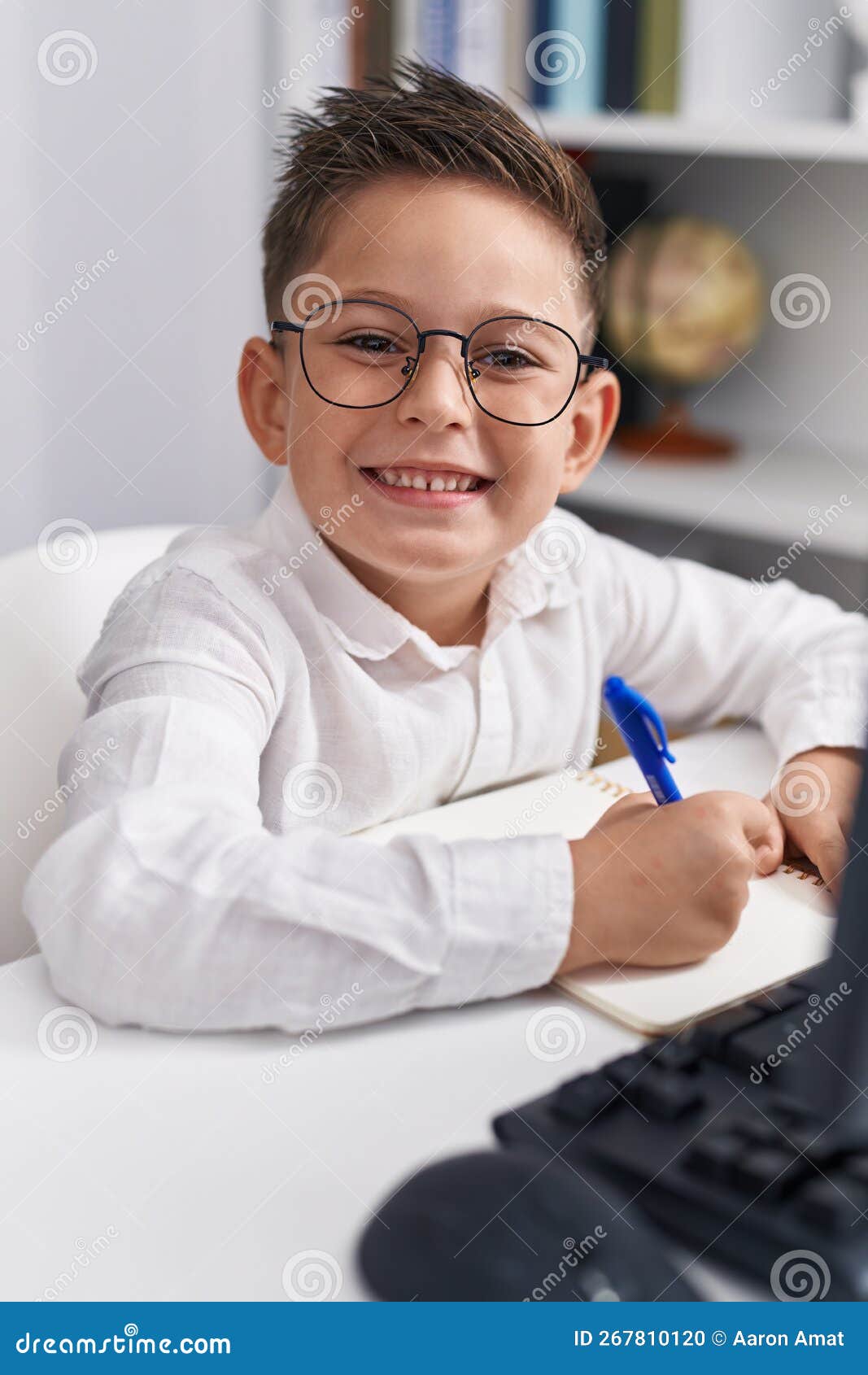 Adorable Hispanic Boy Student Using Computer Writing on Notebook at ...