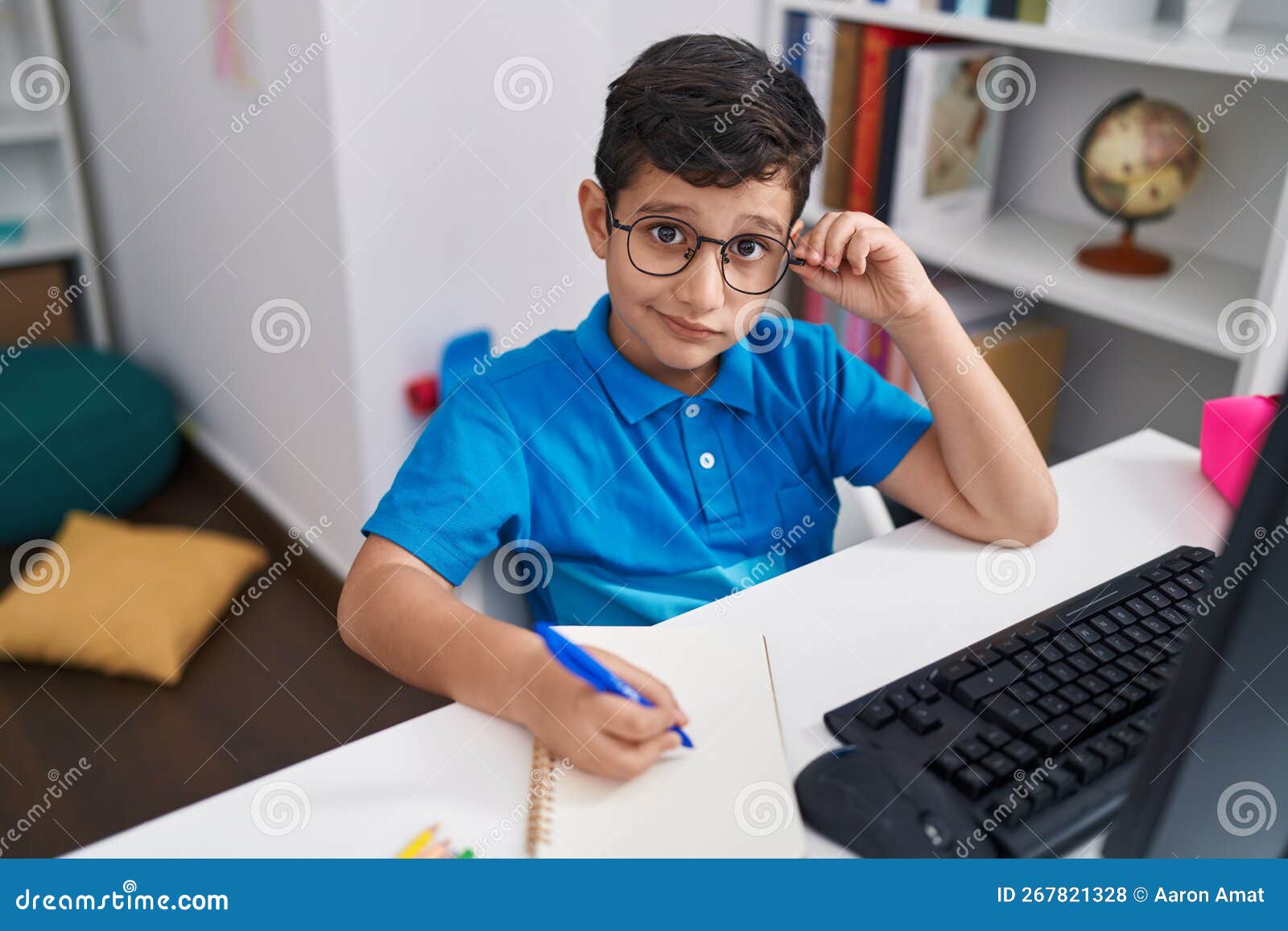 Adorable Hispanic Boy Student Using Computer Writing on Notebook at ...