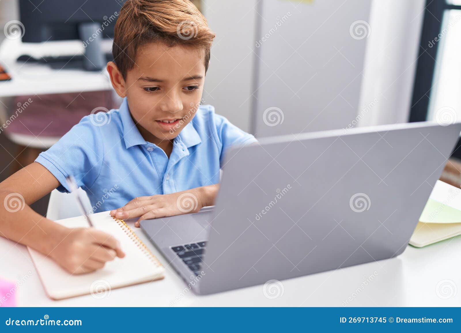 Adorable Hispanic Boy Student Using Computer Writing on Notebook at ...
