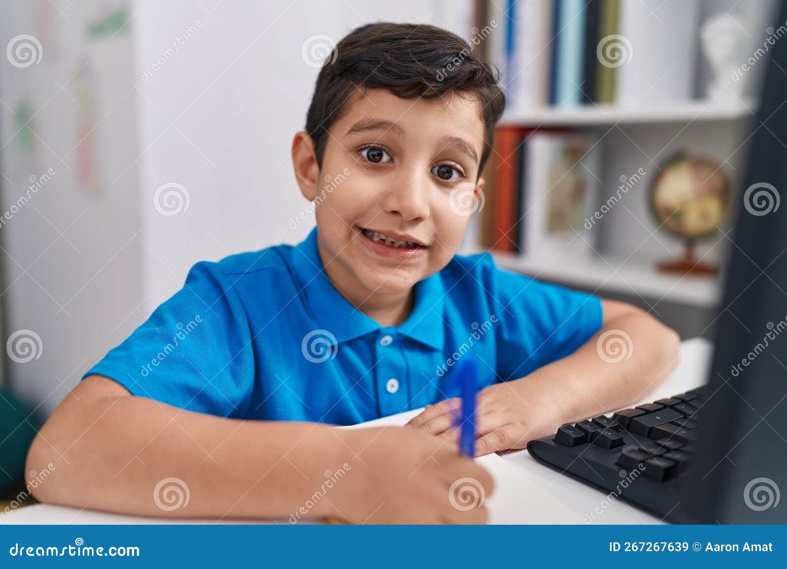 Adorable Hispanic Boy Student Using Computer Writing on Notebook at ...