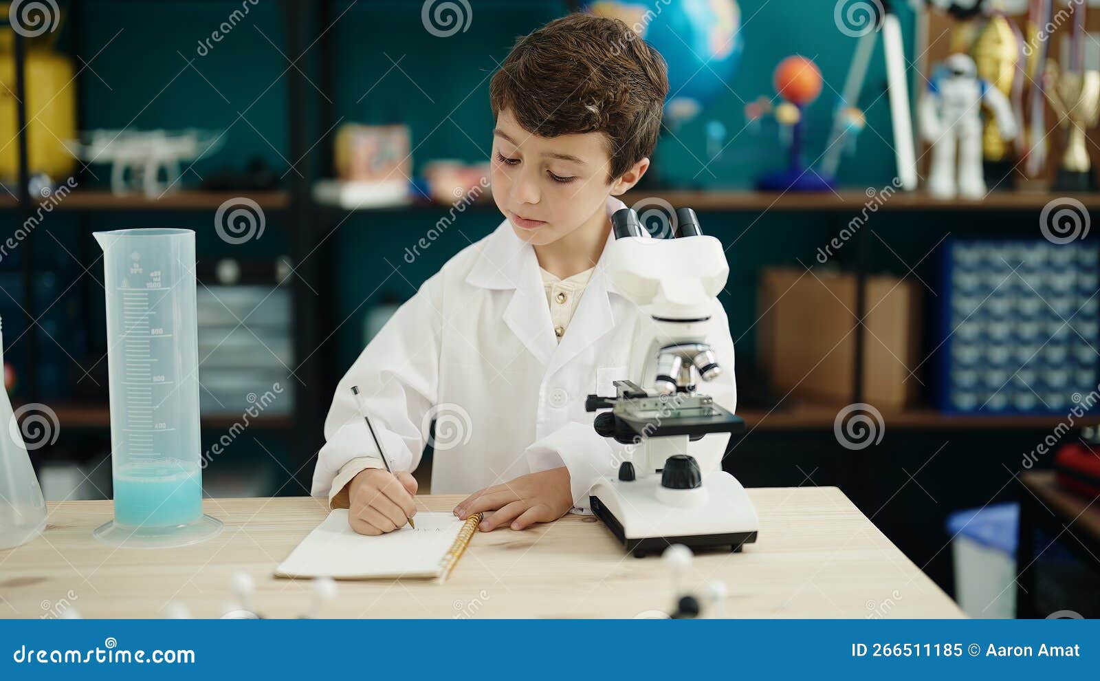 Adorable Hispanic Boy Student Using Microscope Writing on Notebook at ...