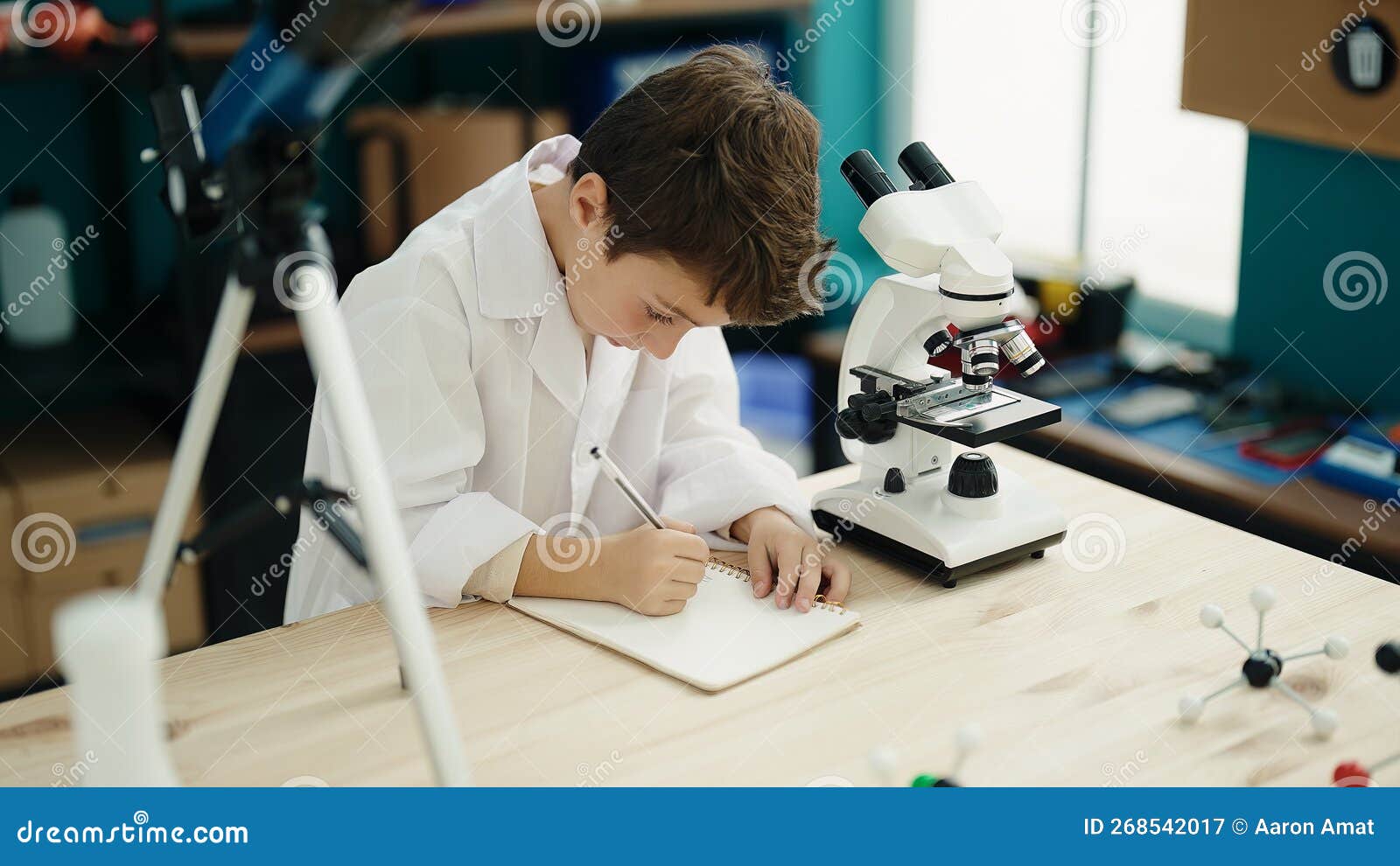 Adorable Hispanic Boy Student Using Microscope Writing on Notebook at ...