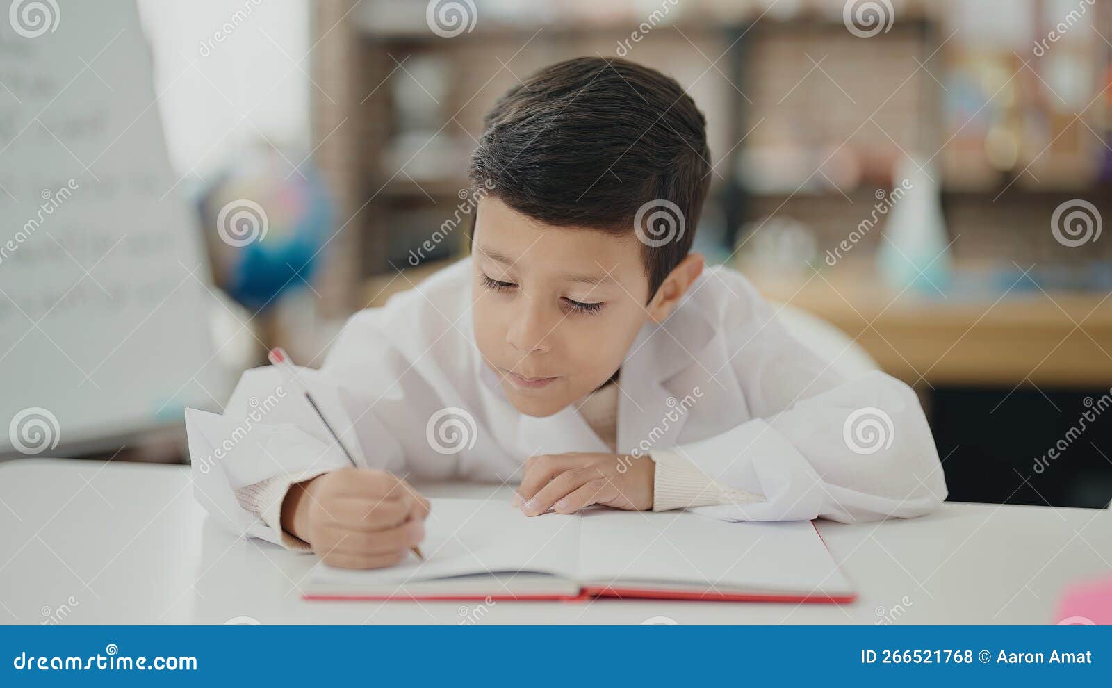 Adorable Hispanic Boy Student Writing on Notebook at Classroom Stock ...