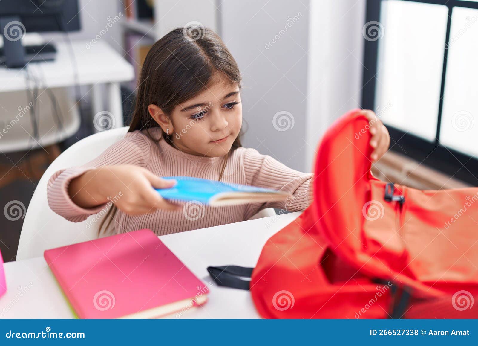 Adorable Hispanic Girl Student Sitting on Table Putting Book on ...