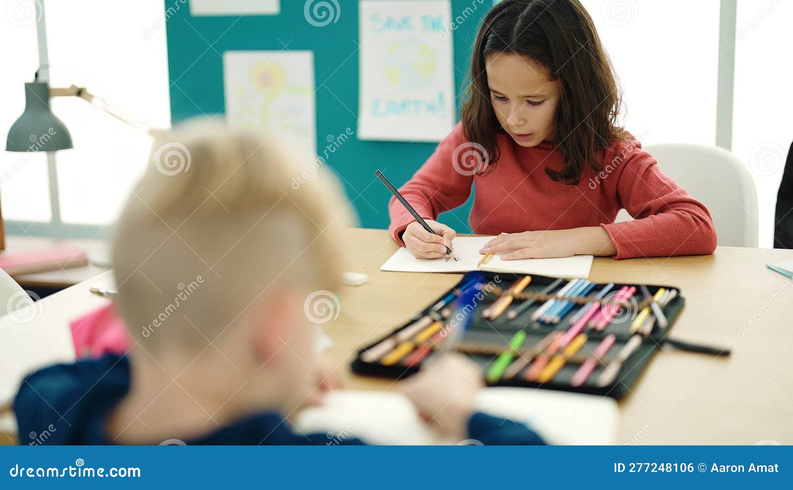 Adorable Hispanic Girl Student Writing on Notebook at Classroom Stock ...