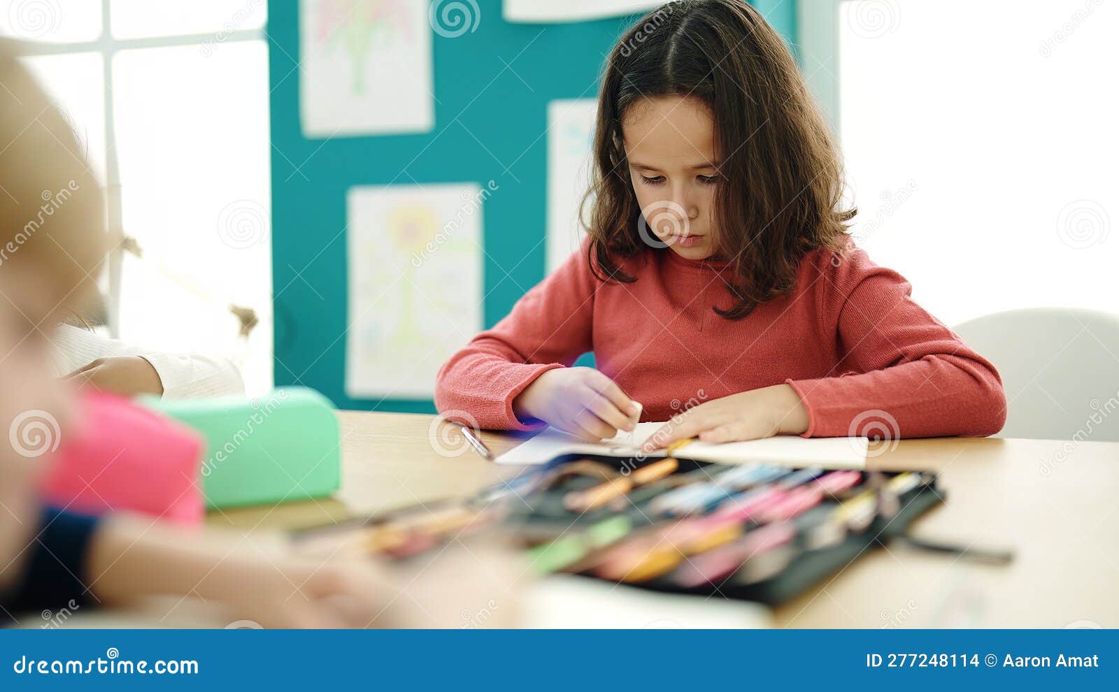 Adorable Hispanic Girl Student Writing on Notebook at Classroom Stock ...