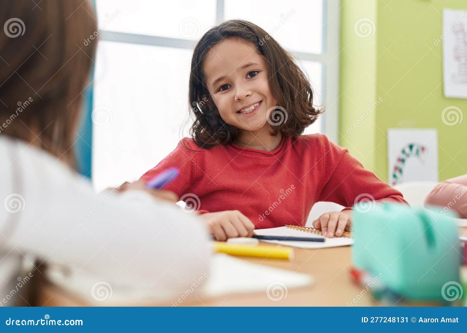 Adorable Hispanic Girl Student Writing on Notebook at Classroom Stock ...