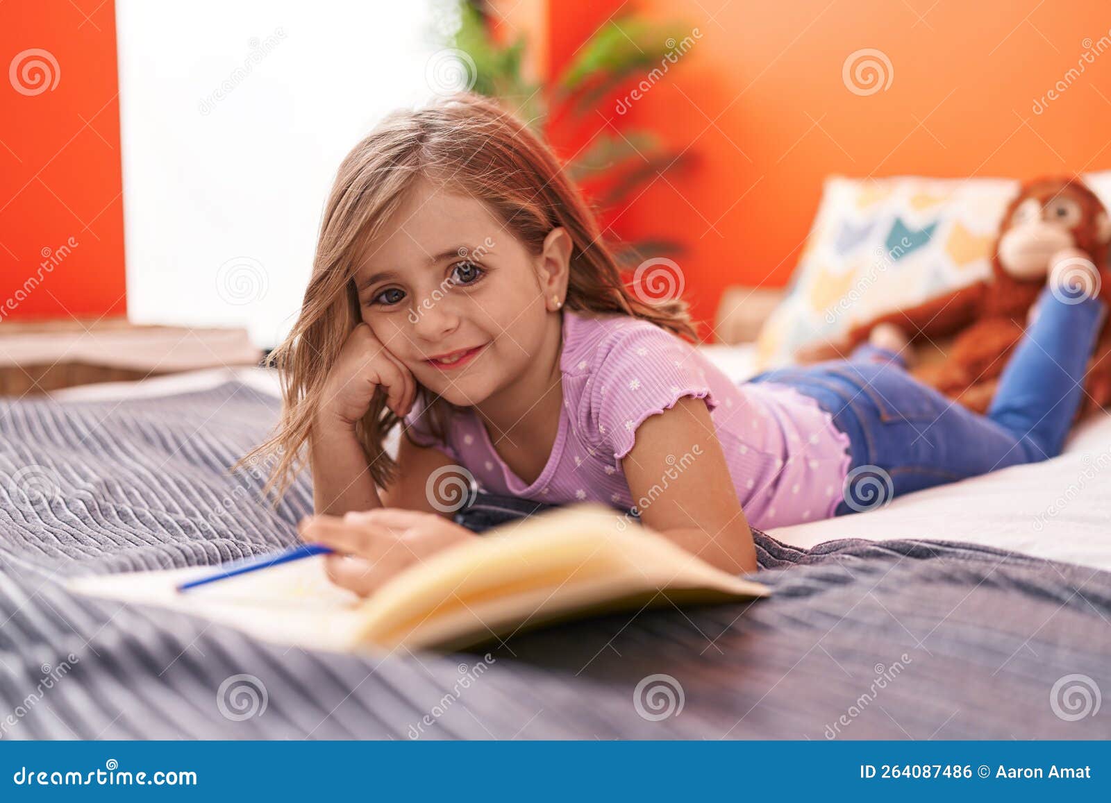 Adorable Hispanic Girl Writing on Notebook Lying on Bed at Bedroom ...