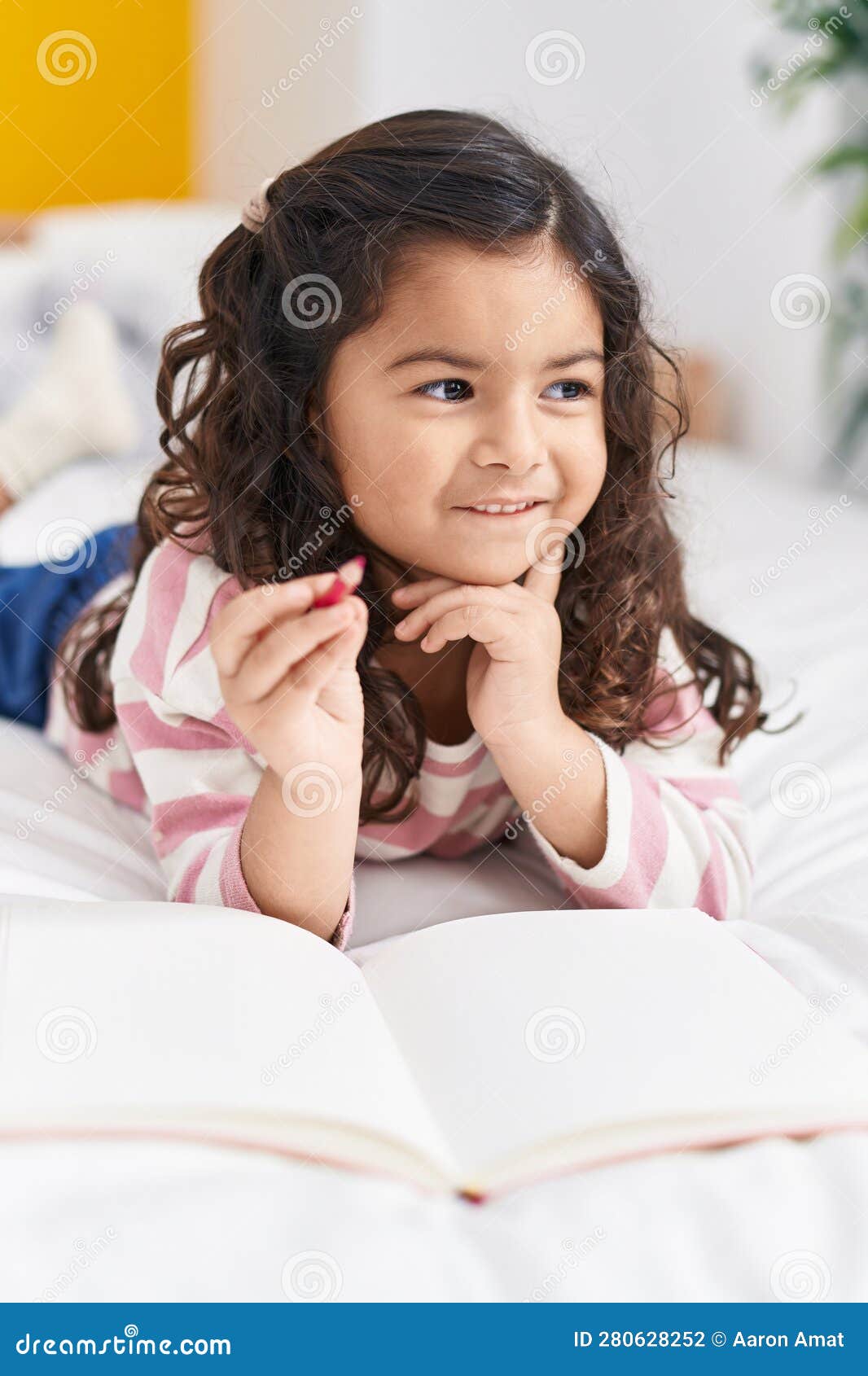 Adorable Hispanic Girl Writing on Notebook Lying on Bed Thinking at ...