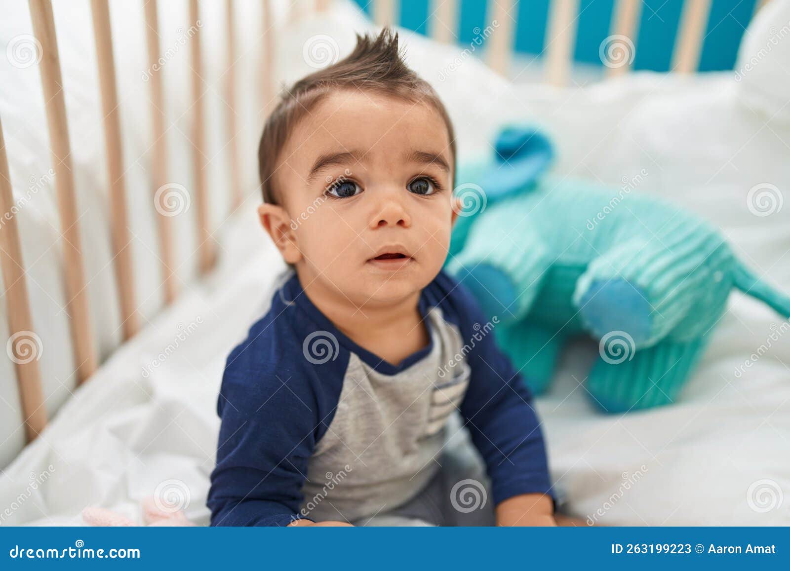 Adorable Hispanic Toddler Sitting on Cradle with Relaxed Expression at ...
