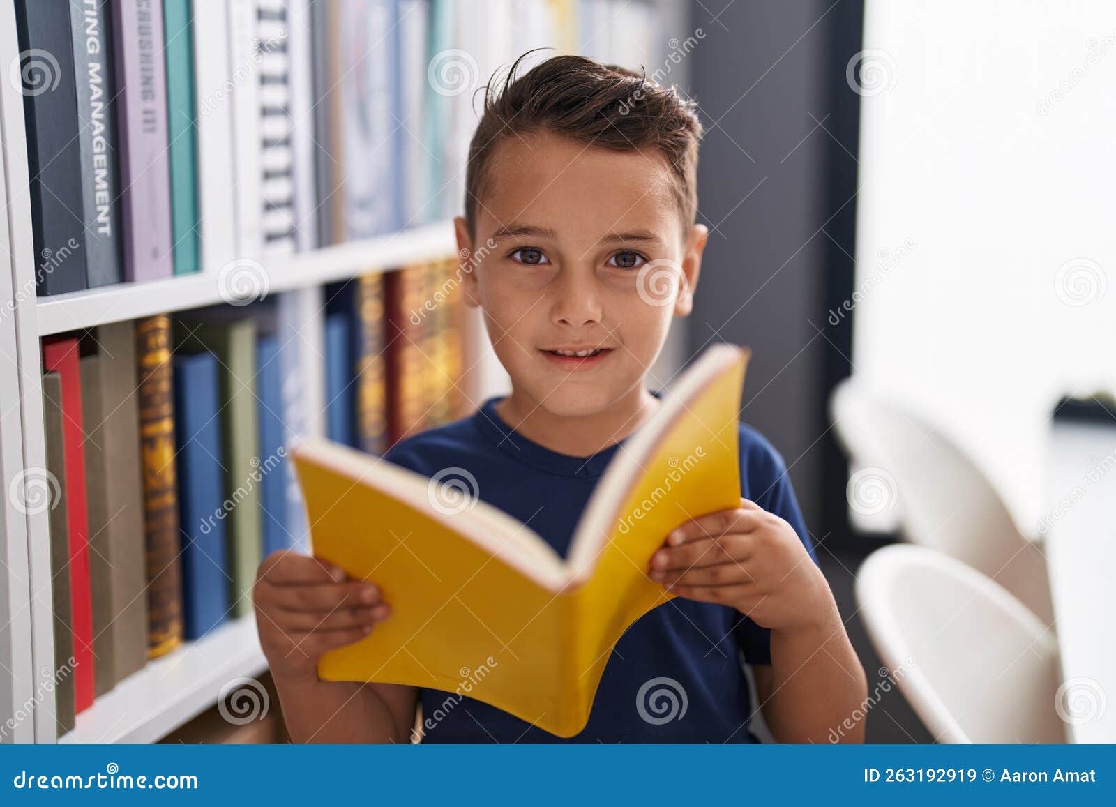 Adorable Hispanic Toddler Student Reading Book Standing at Library ...