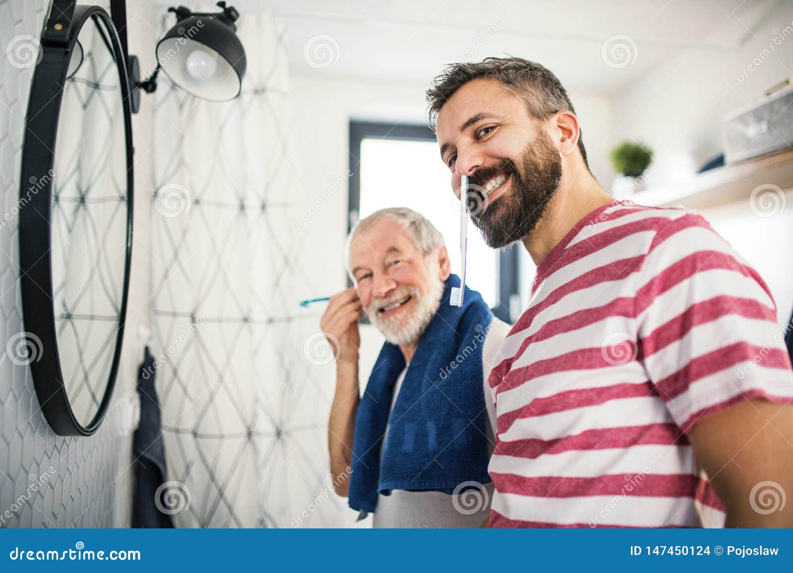 An Adult Hipster Son And Senior Father In Bathroom Indoors At Home