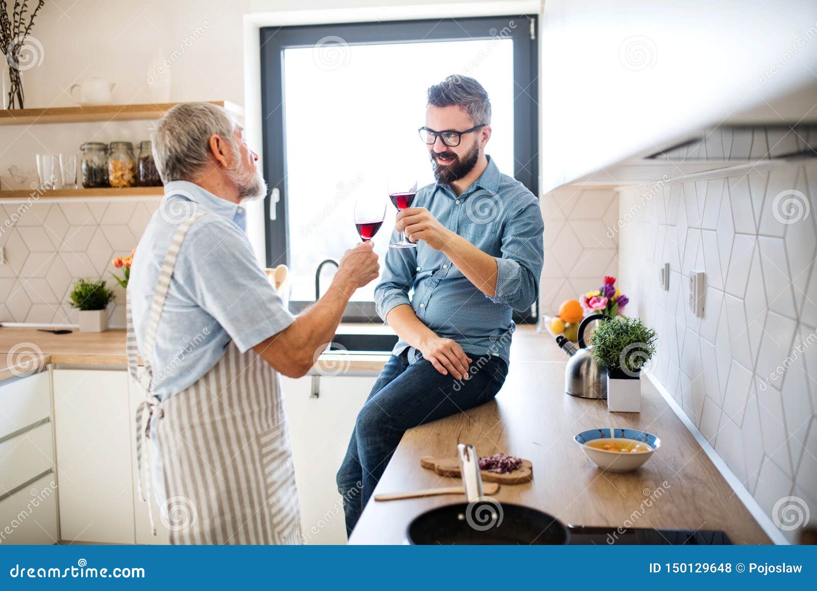 An Adult Hipster Son And Senior Father Indoors In Kitchen At Home
