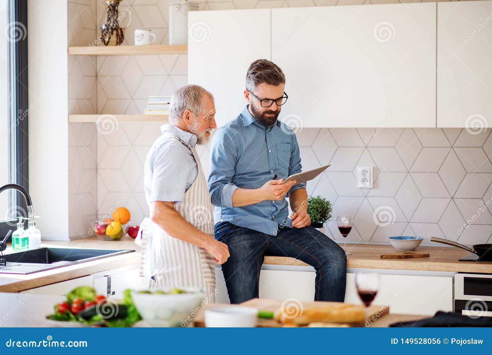 Adult Hipster Son And Senior Father Indoors In Kitchen At Home Using
