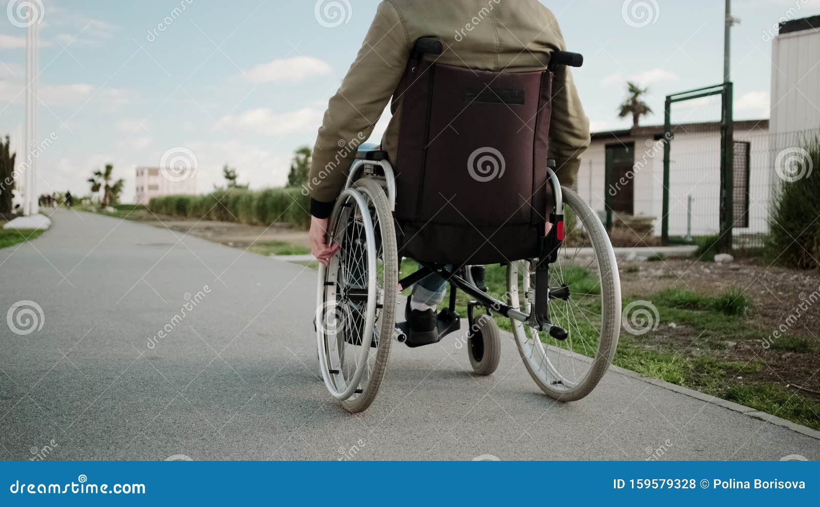 Disabled Man in a Wheelchair is Moving Over Summer Street, Back View ... Disabled Man in a Wheelchair is Moving Over Summer Street, Back View ...