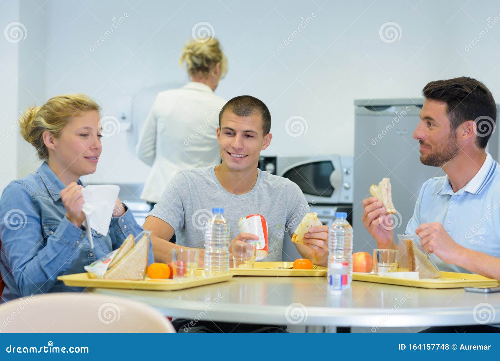 Adults Sat Around Table Eating Packed Lunches Off Trays Stock Photo ...