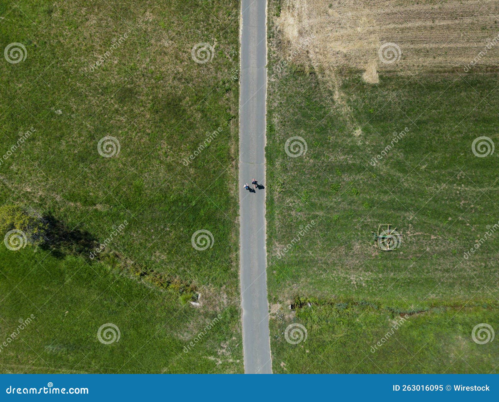 Aerial Shot of an Asphalt Road with Two Men Running on it Surrounded by ...