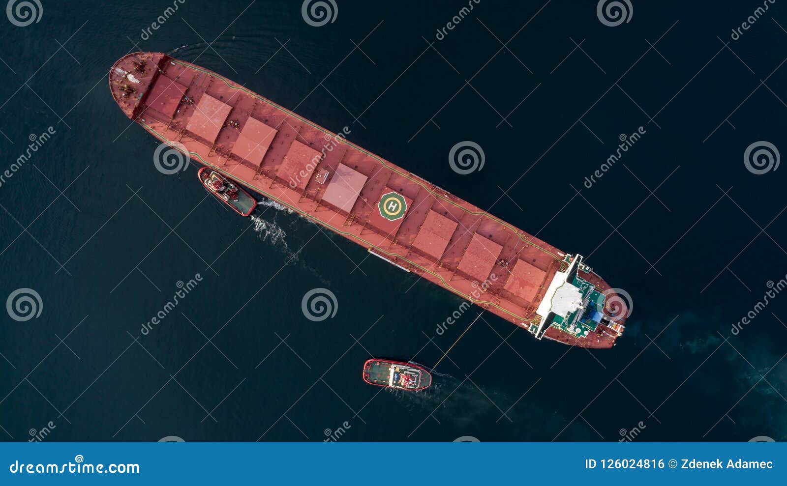 Aerial Shot of a Cargo Ship Approaching Port with Help of Towing Ship ...