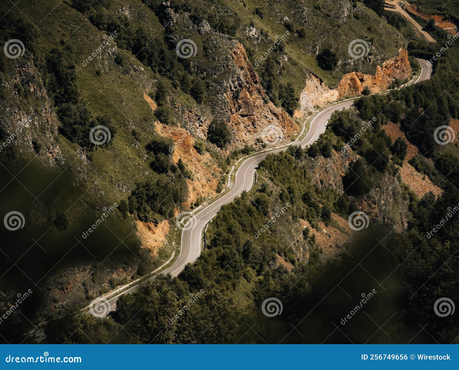Aerial Shot of a Road Going Along the Side of a Green Mountian Stock ...