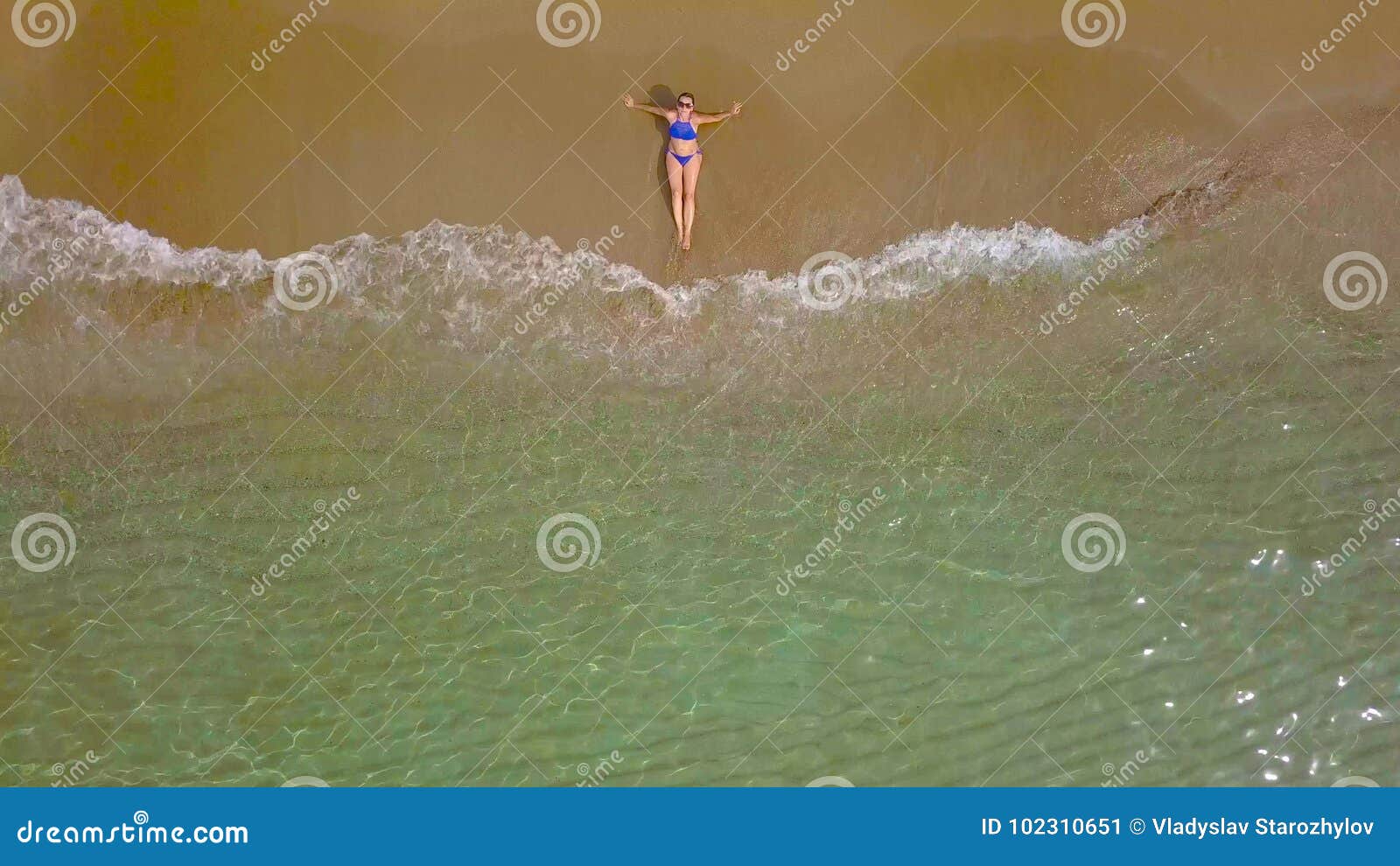 Aerial Shot Of A Woman In A Bikini Lying On A Sandy Beach And Waves
