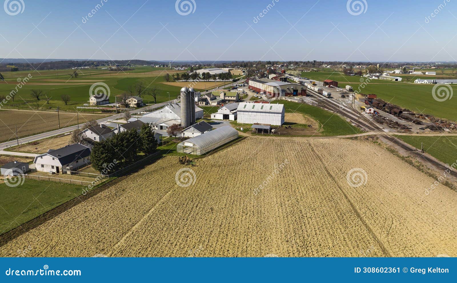 Aerial View of a Farm Complex with Multiple Barns, Silos, and Plowed ...