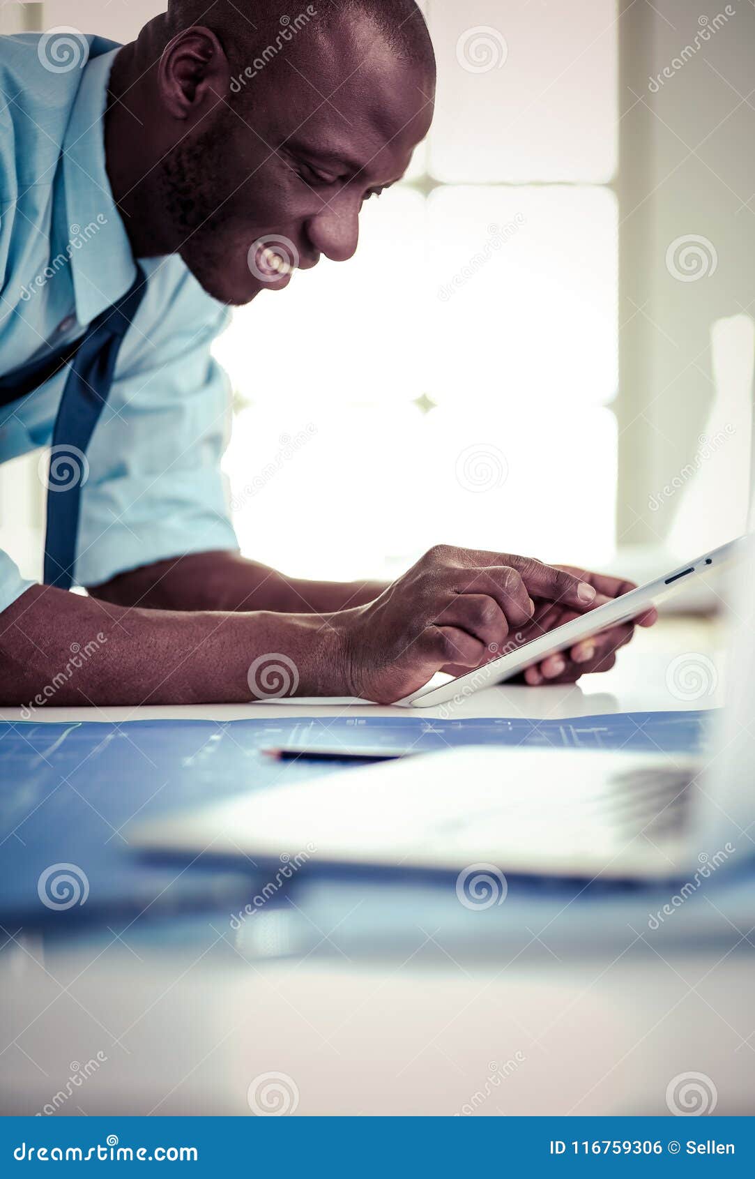 African American Architect Working with Computer and Blueprints in ...