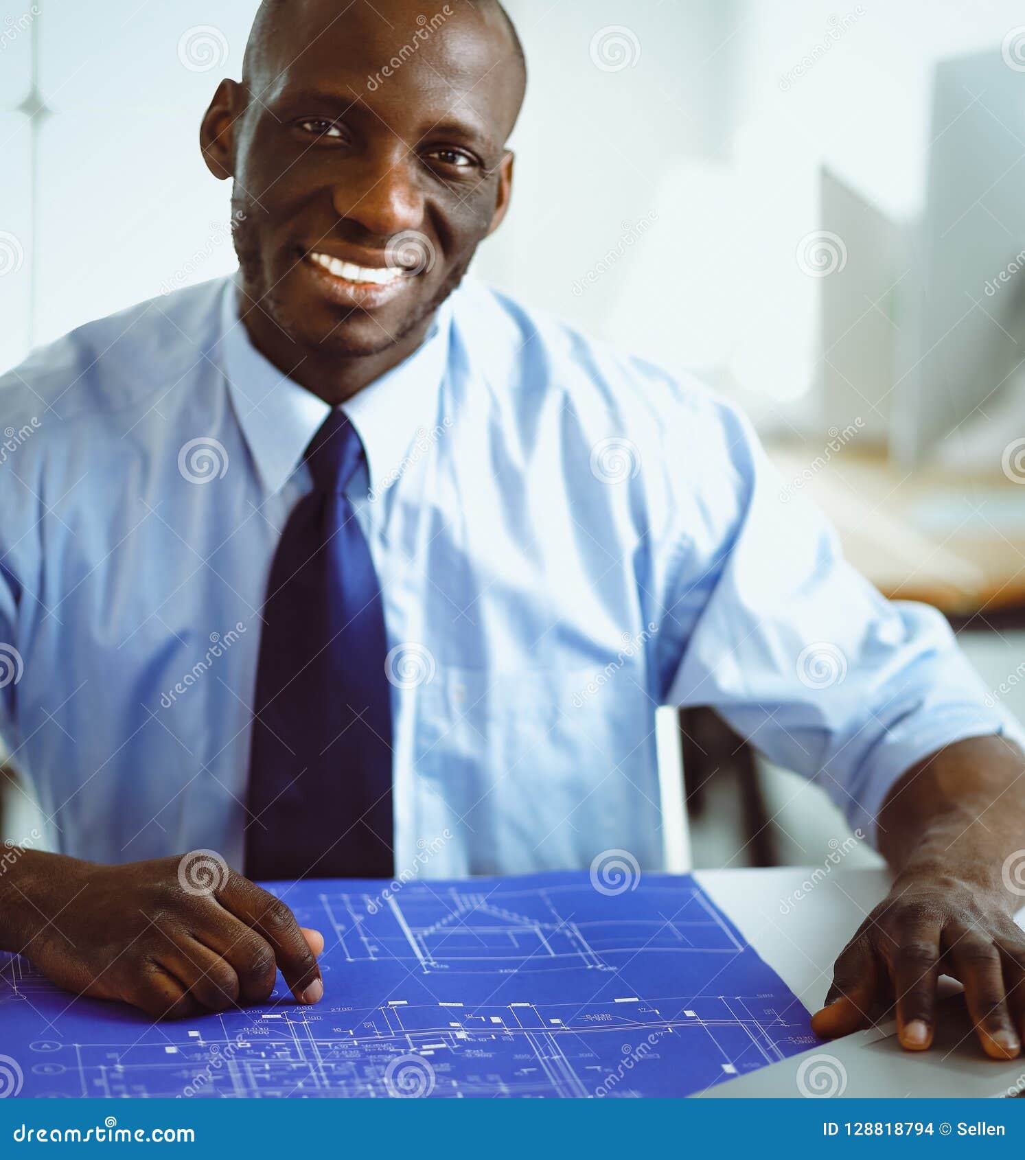 African American Architect Working with Computer and Blueprints in ...