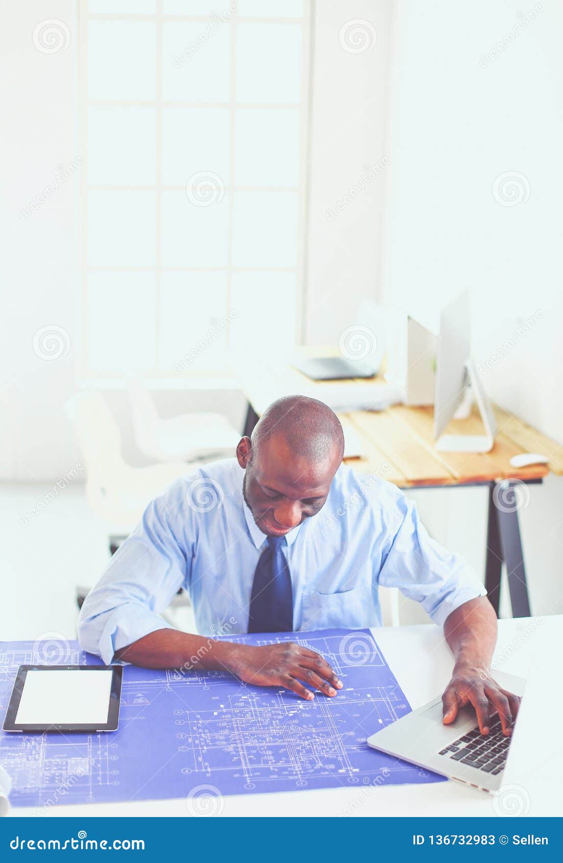 African American Architect Working with Computer and Blueprints in ...