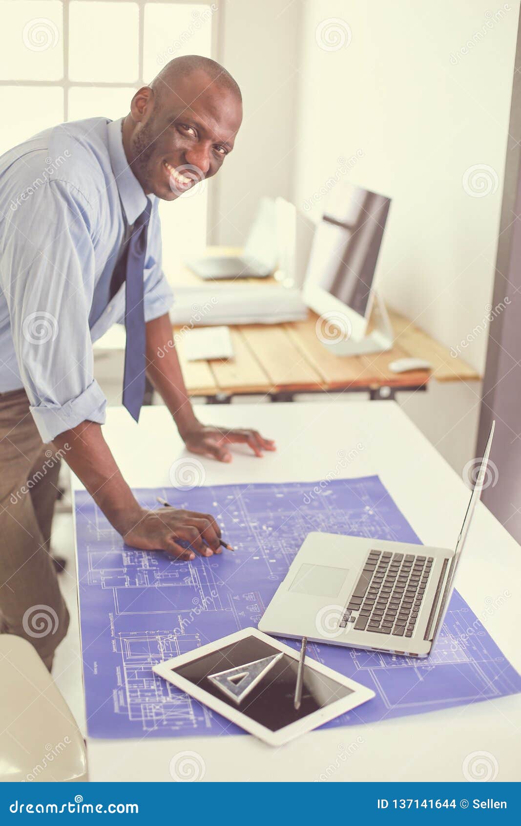 African American Architect Working with Computer and Blueprints in ...