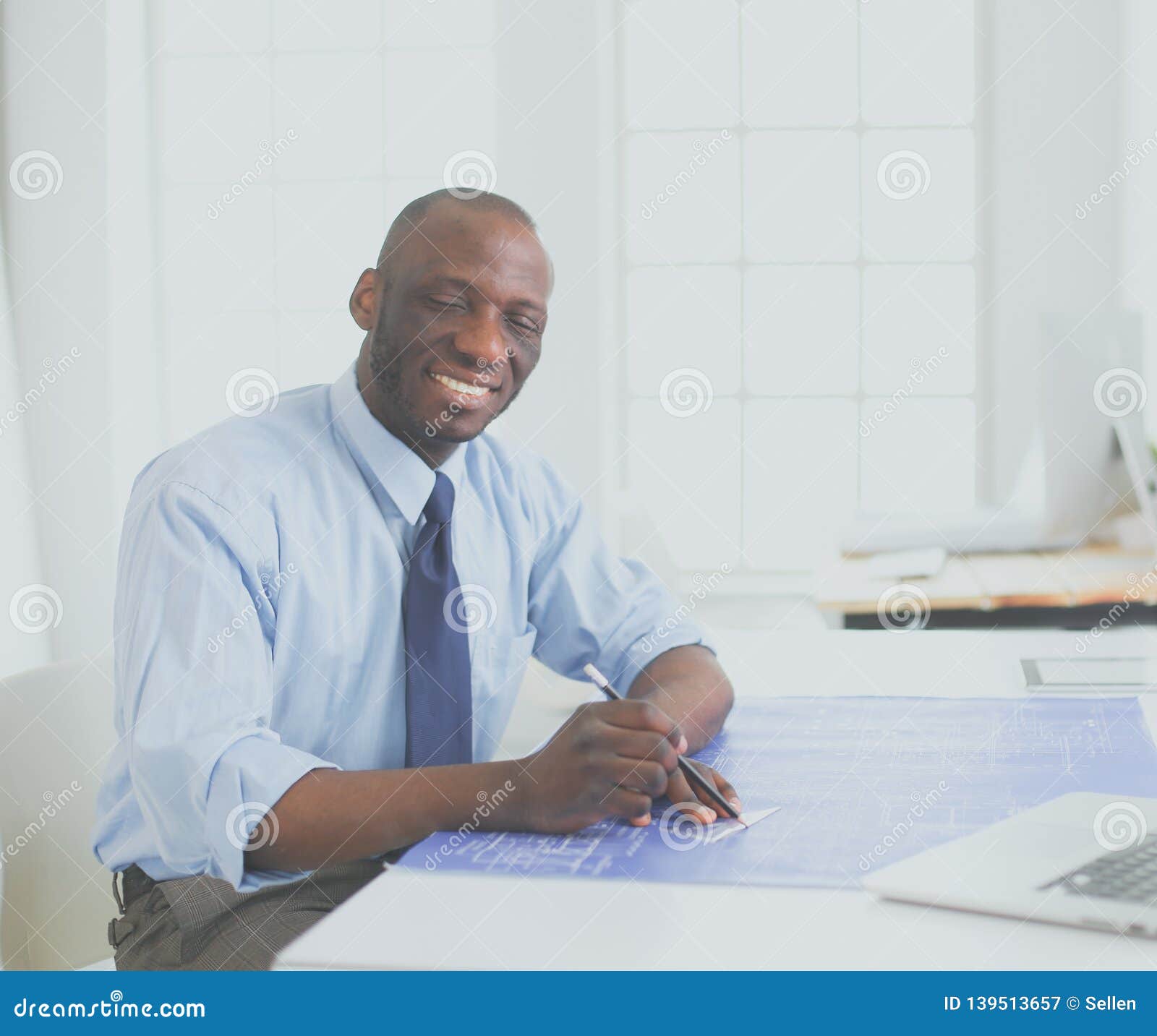 African American Architect Working with Computer and Blueprints in ...