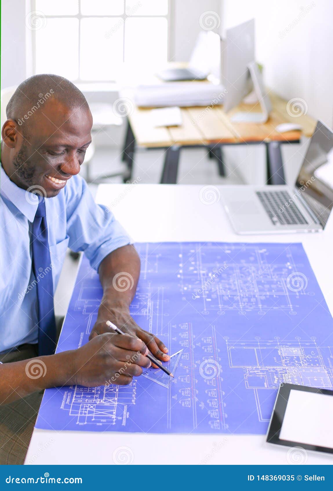 African American Architect Working with Computer and Blueprints in ...