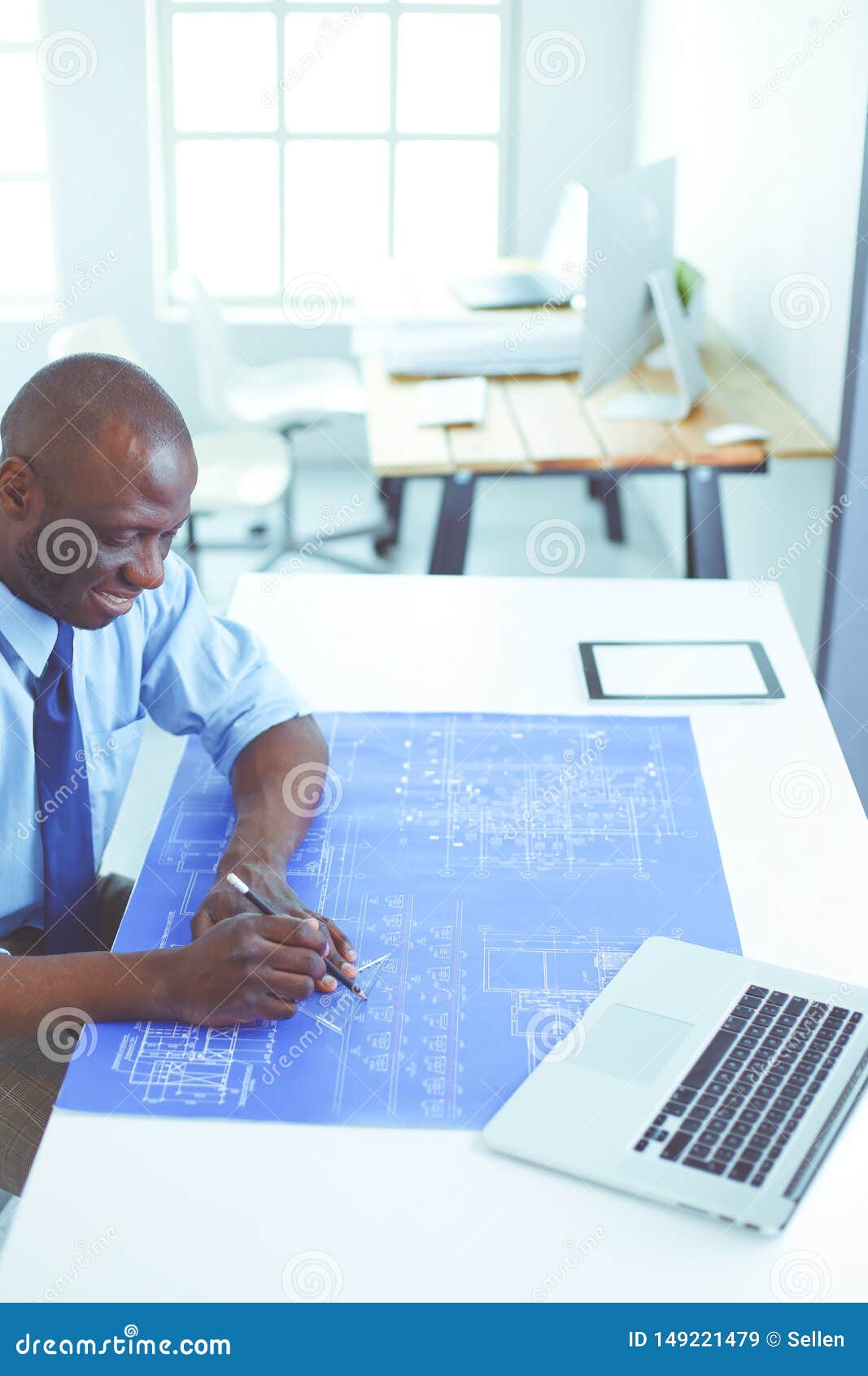 African American Architect Working with Computer and Blueprints in ...