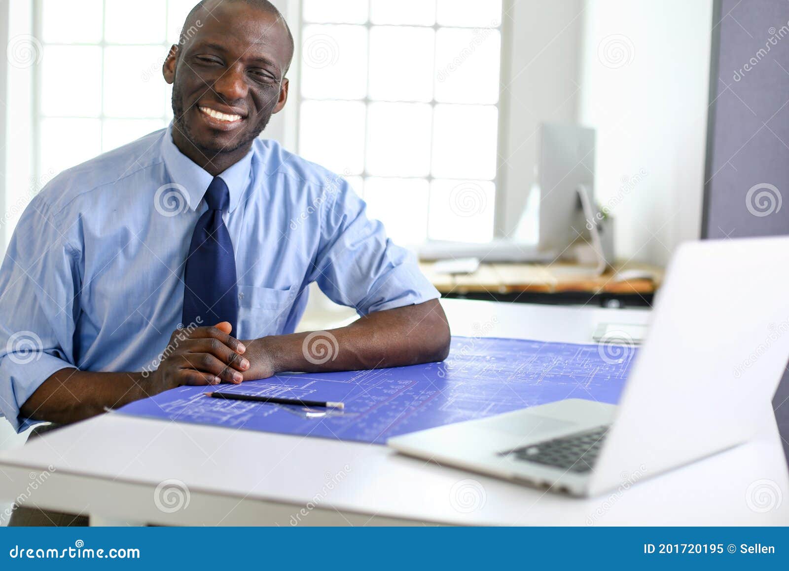 African American Architect Working with Computer and Blueprints in ...