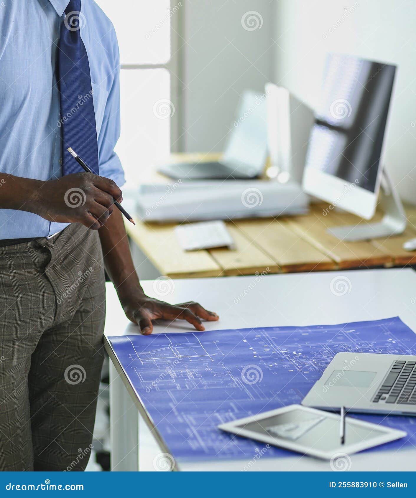 African American Architect Working with Computer and Blueprints in ...