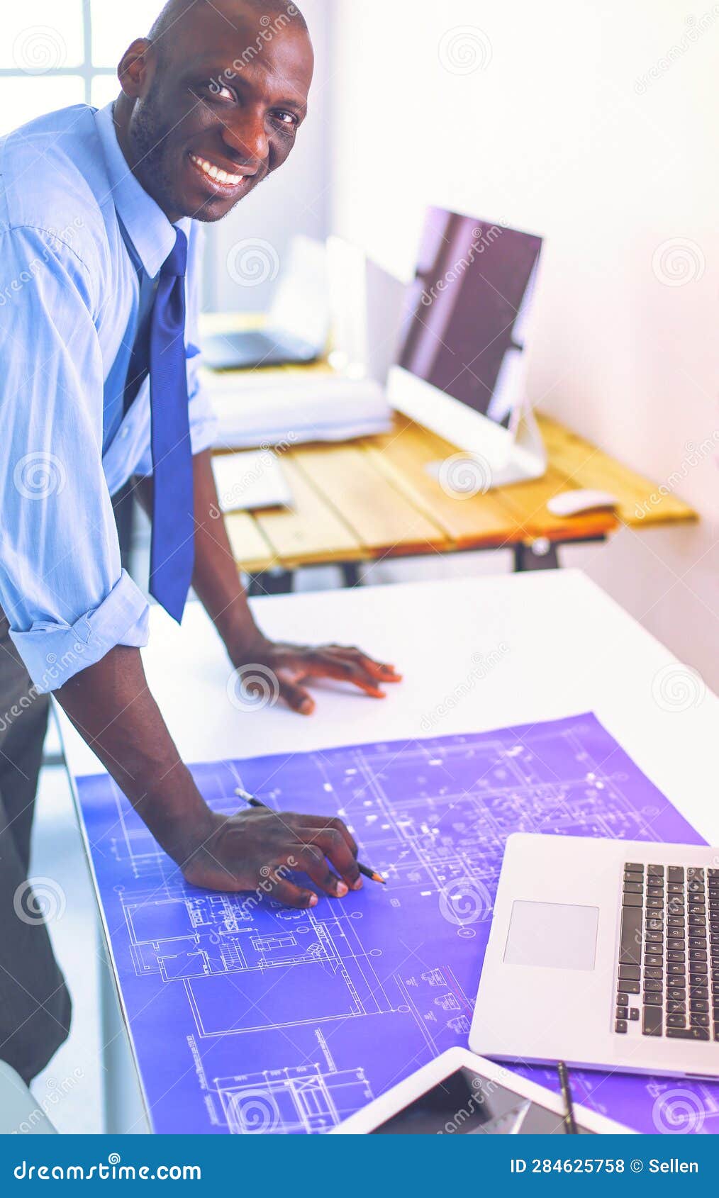 African American Architect Working with Computer and Blueprints in ...