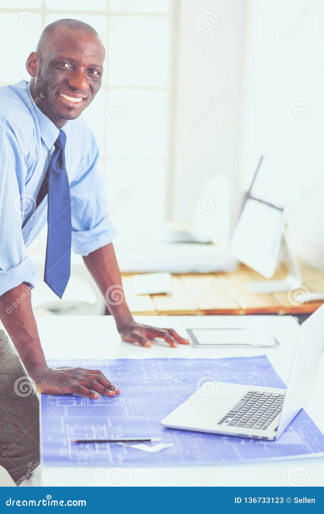 African American Architect Working with Computer and Blueprints in ...