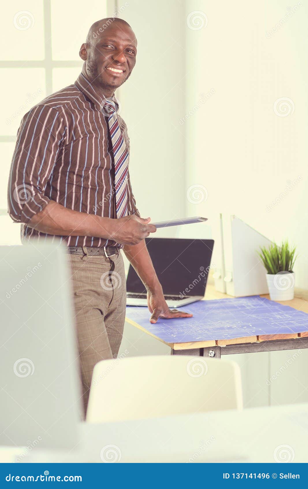 African American Architect Working with Computer and Blueprints in ...