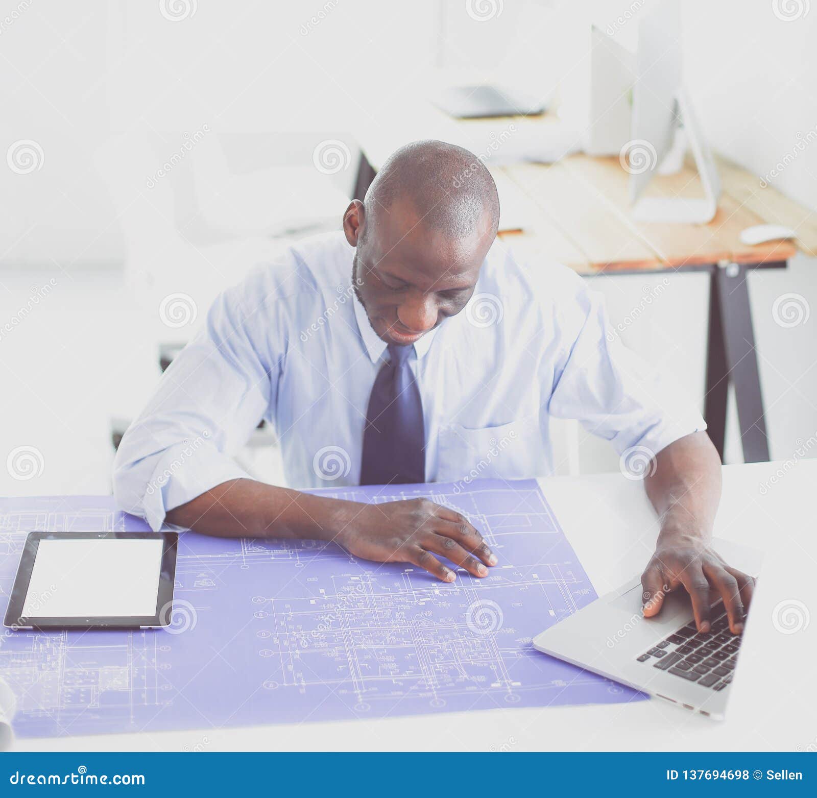 African American Architect Working with Computer and Blueprints in ...