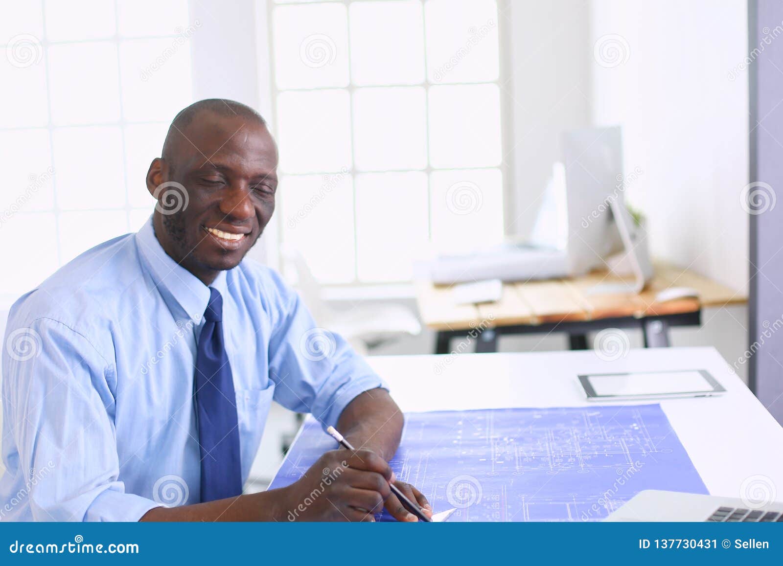 African American Architect Working with Computer and Blueprints in ...