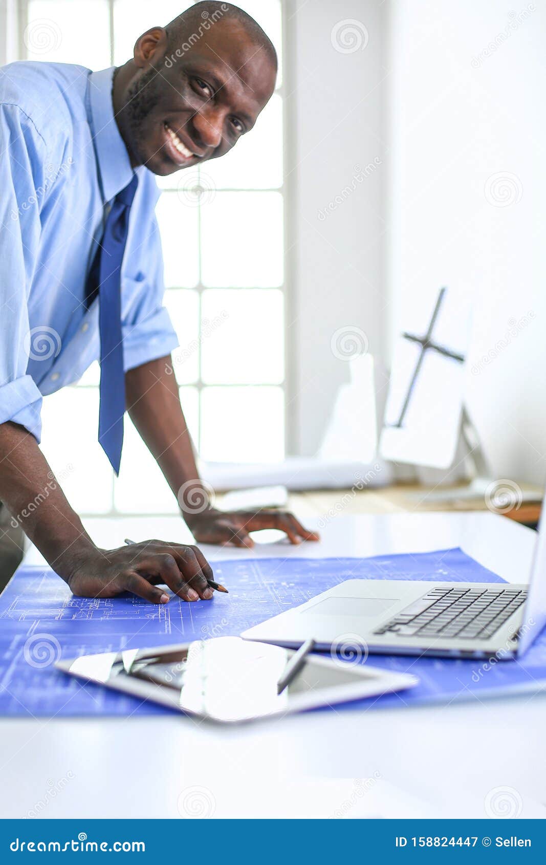 African American Architect Working with Computer and Blueprints in ...