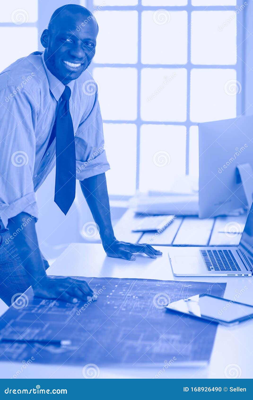 African American Architect Working with Computer and Blueprints in ...