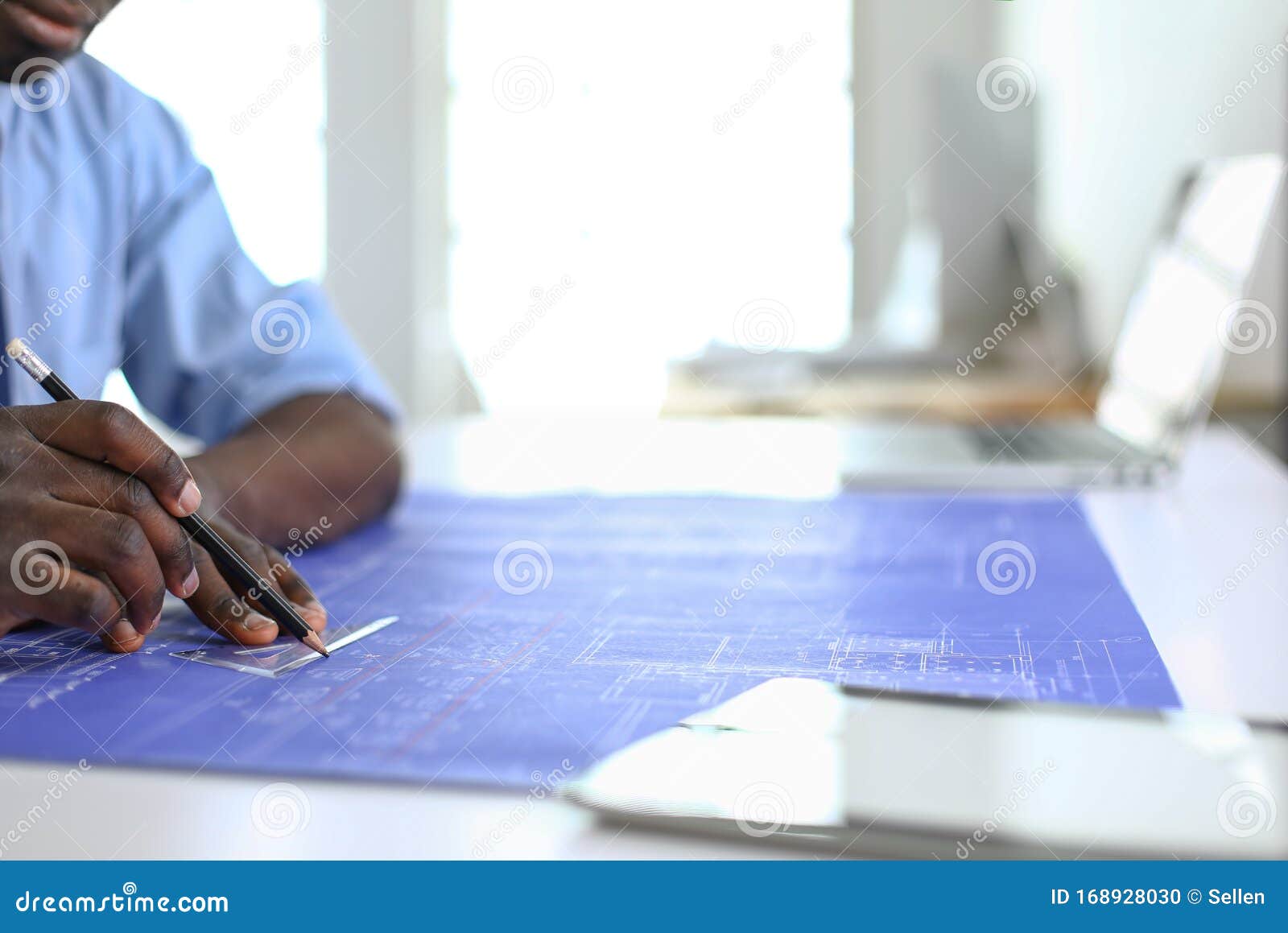African American Architect Working with Computer and Blueprints in ...