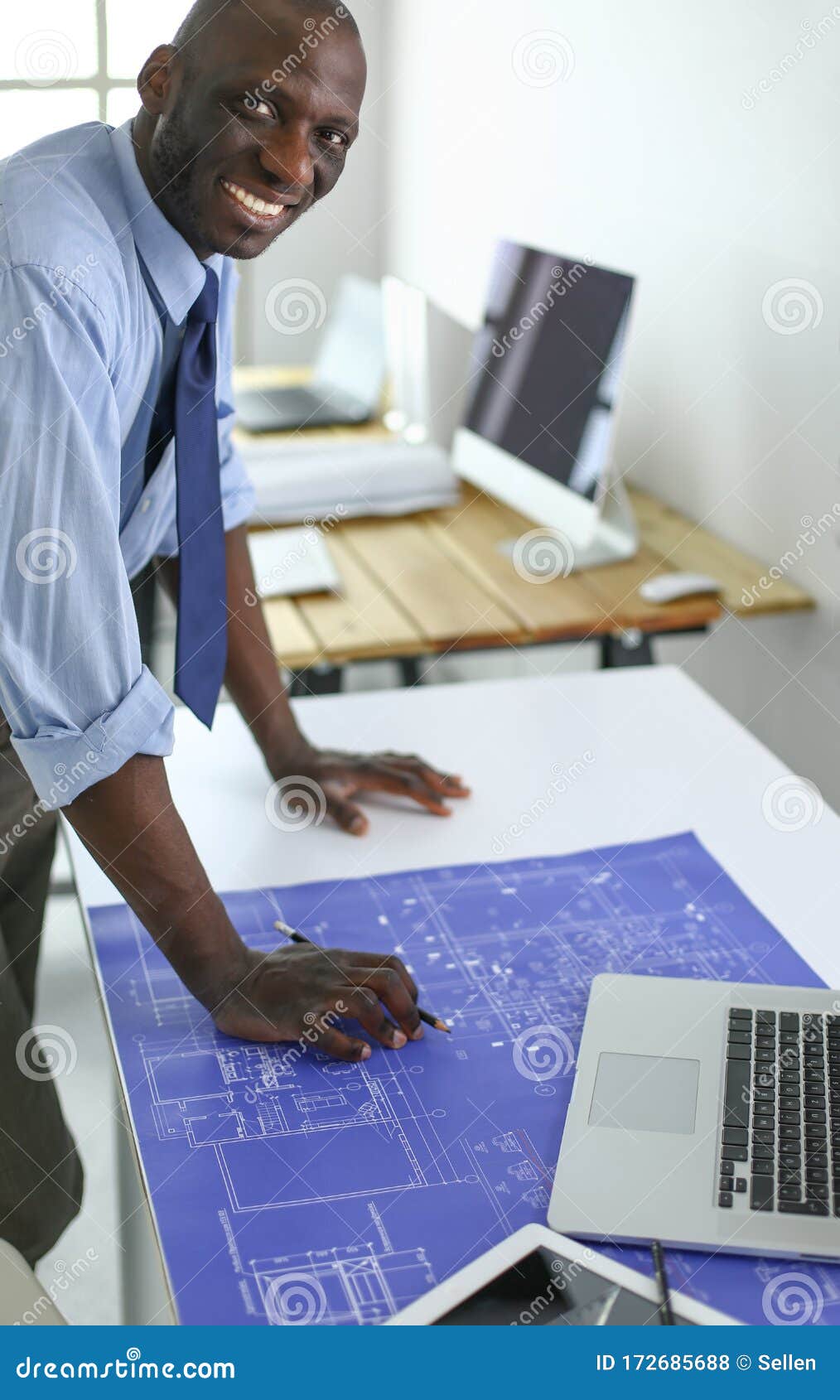 African American Architect Working with Computer and Blueprints in ...