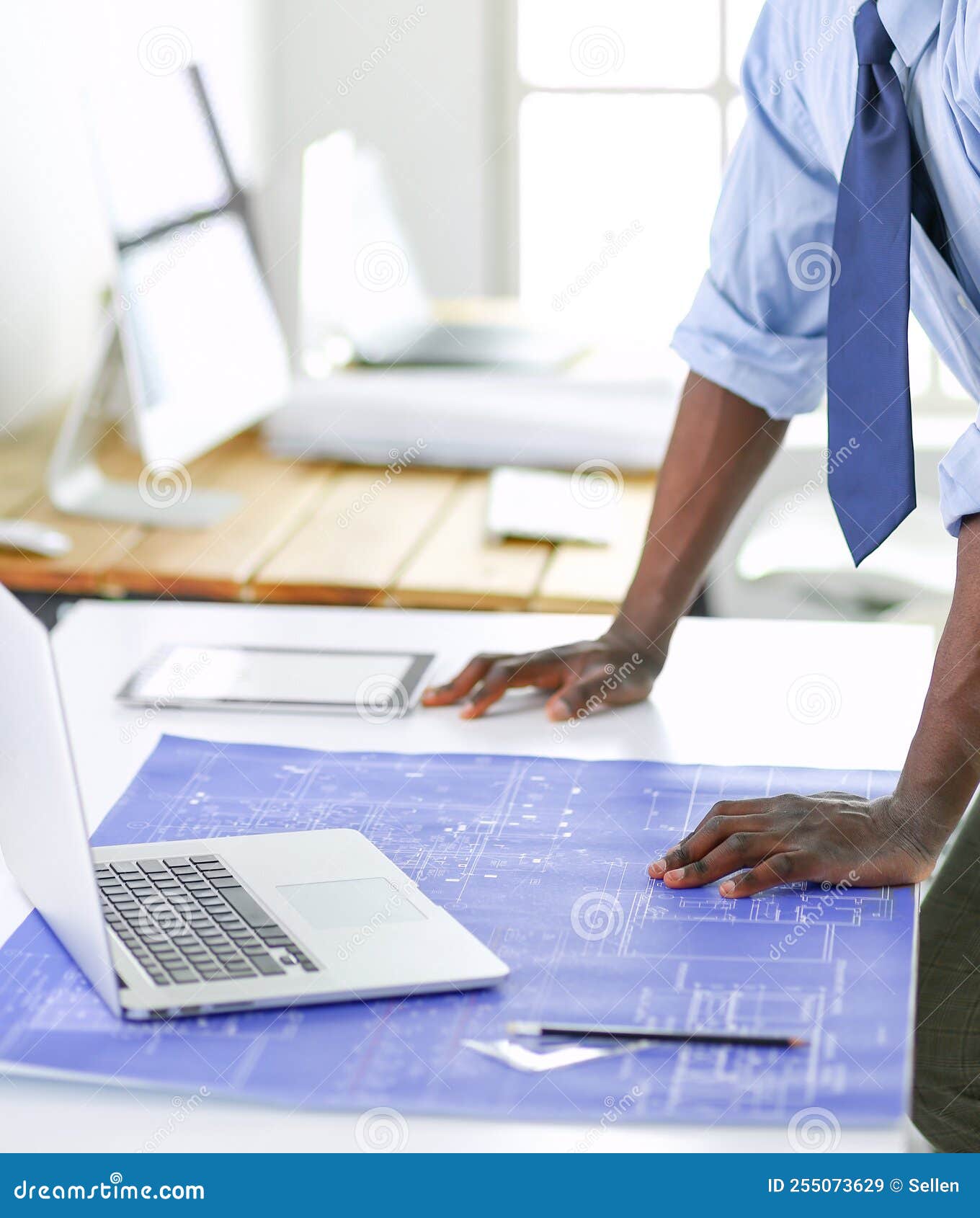 African American Architect Working with Computer and Blueprints in ...