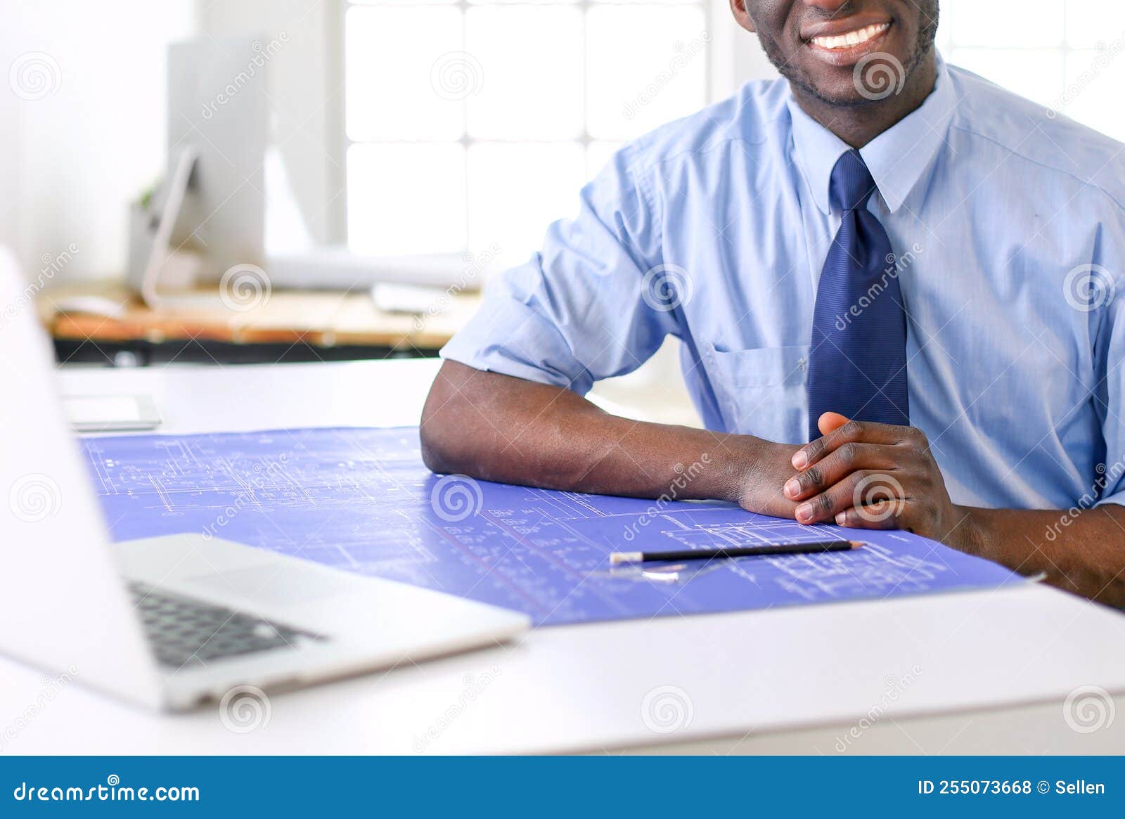 African American Architect Working with Computer and Blueprints in ...