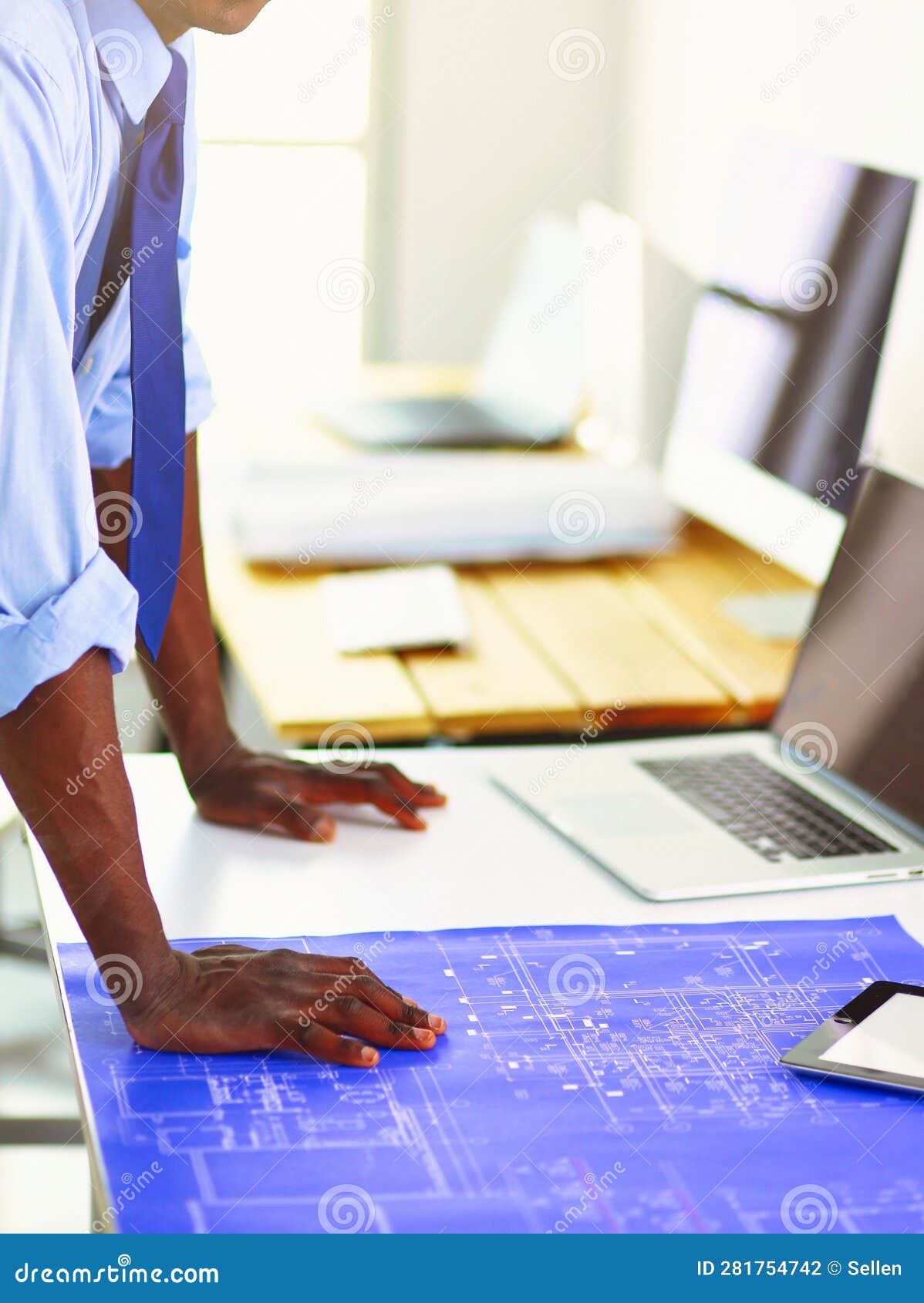African American Architect Working with Computer and Blueprints in ...