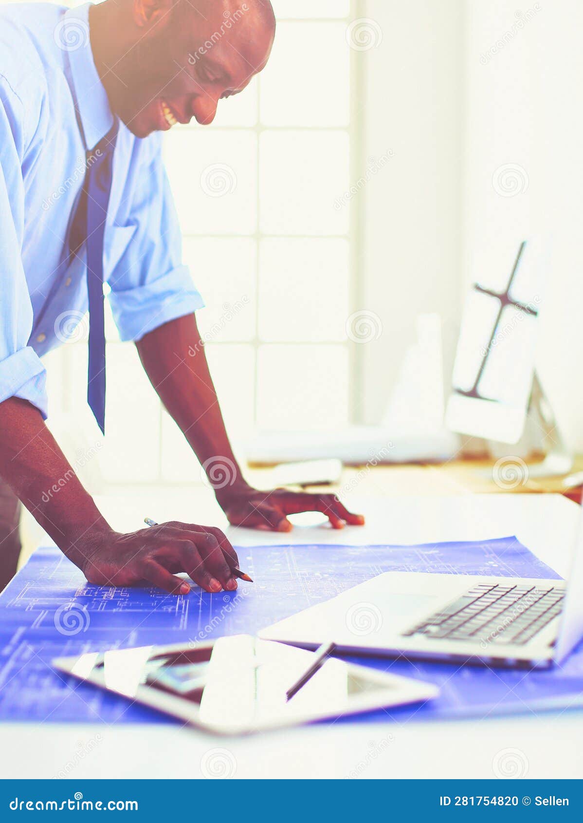 African American Architect Working with Computer and Blueprints in ...