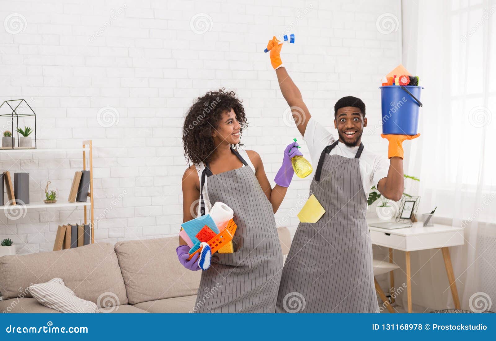 African American Couple Holding Cleaning Tools And Detergents Stock