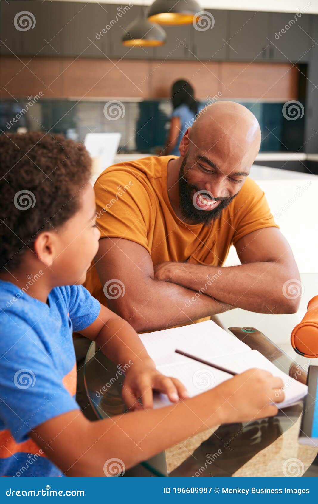 African American Father Helping Son Studying Homework in Kitchen Stock ...